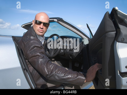 Bald man driving in an open top classic Porsche car on a warm sunny day ...