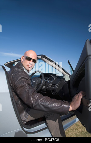 Bald man driving in an open top classic Porsche car on a warm sunny day ...