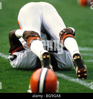 American football player stretches out his taped ankle before a game ...