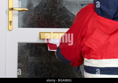 postman posting letters and cards through the letterbox of a house in ...