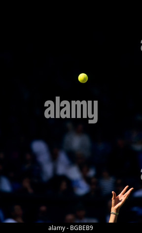 Tennis player throwing a ball in the air hitting a serve. Player is ...