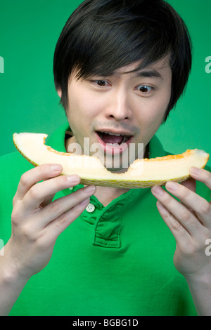 Young man holding a melon as mouth in front of his face, Bavaria ...