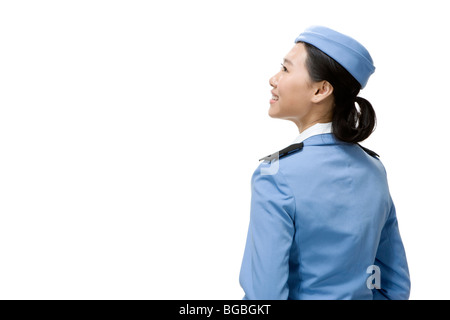 Rear view of young flight attendant walking in airport with lens flare ...