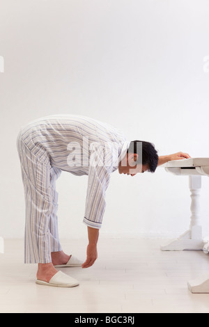 Side view of man stretching on wooden walkway by river against sky ...