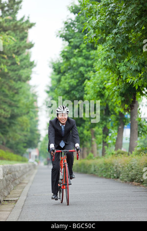 Smiling businessman riding a bicycle Stock Photo - Alamy