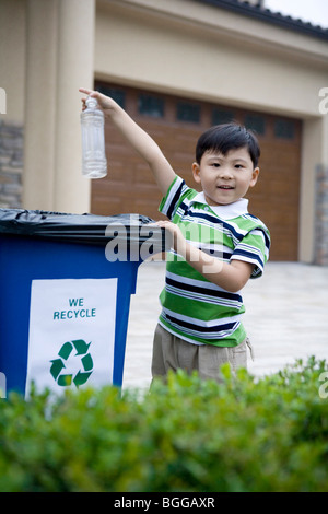 Young boy throwing a plastic bottle into the recycle bin Stock Photo ...