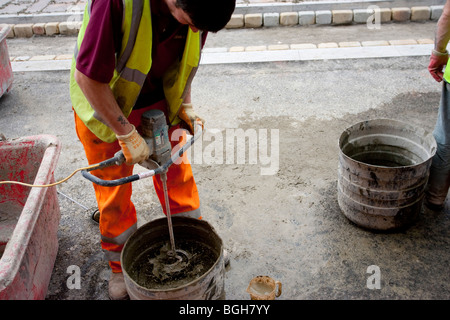 Concrete & cement being prepared by spade & shovel and hand powered ...