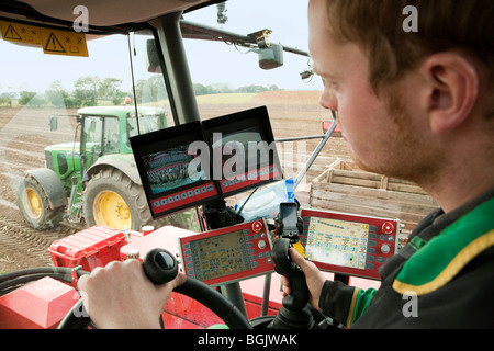Interior of a tractor cab showing computer and controls with hand of ...