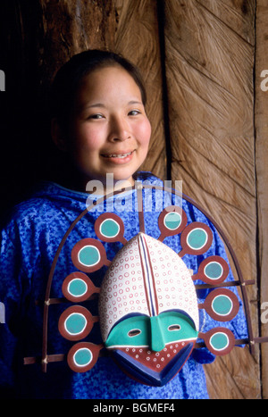 Inuit teenage girl holds up a traditional seal skin parka coat in the ...