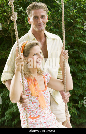 Men holding a rope and a mature woman jumping isolated on white ...