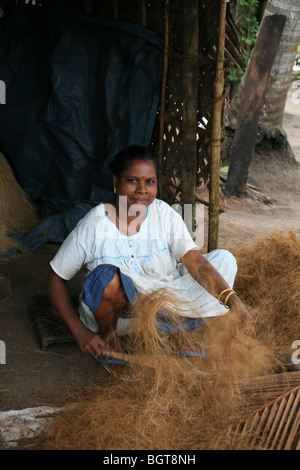 Indian woman making rope from coir extracted from coconut husks in ...