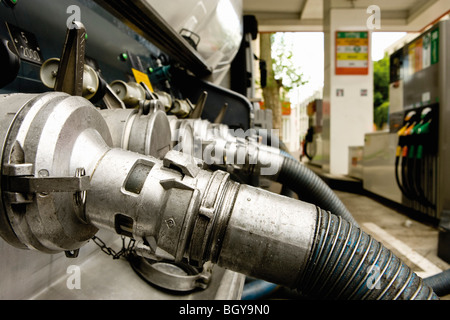 Hoses connected to fuel tanker outlets transferring fuel to gas station ...