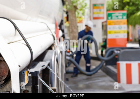 Hoses connected to fuel tanker outlets transferring fuel to gas station ...