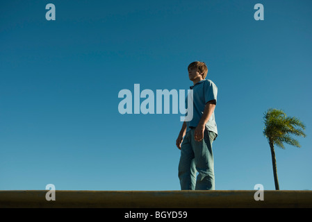 Young man standing on ledge, looking at the Half Dome, view from ...