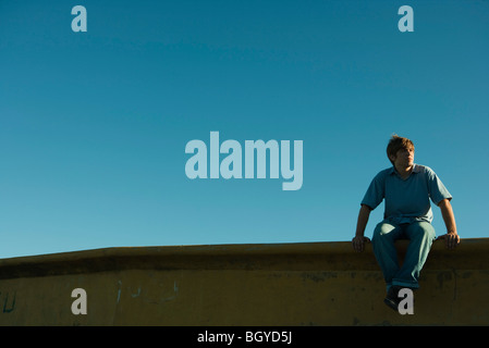 A man sits on a ledge looking over Teotihuacán, an ancient Mesoamerican ...