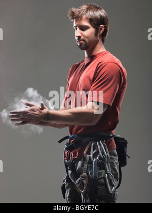 Use the chalk. a young man putting chalk powder on his hands at the gym ...