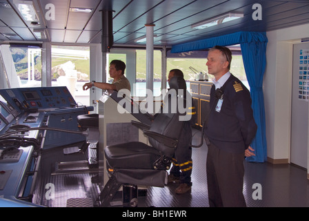 Captain and crew members on the bridge of a ship as it enters port ...