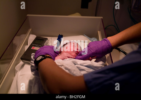 nurse taking temperature of newborn baby born by cesarian section, in ...