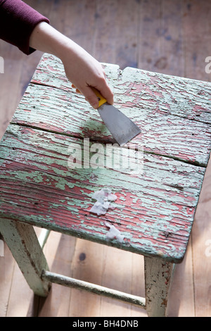 Scraping old peeling paint with a hand scraper from a wide plank wood ...