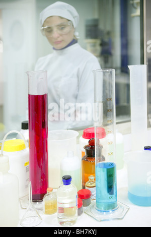 In a laboratory, a woman in a red lab coat observes a large wooden ...