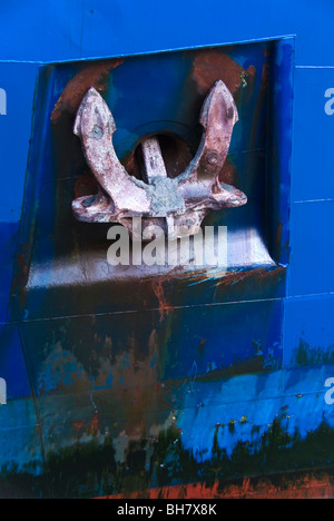 A close - up view of a ship's anchor housed in it's hawse pipe recessed ...