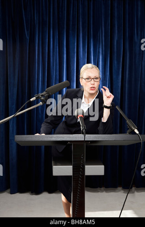 A woman in a suit speaking at a lectern Stock Photo - Alamy