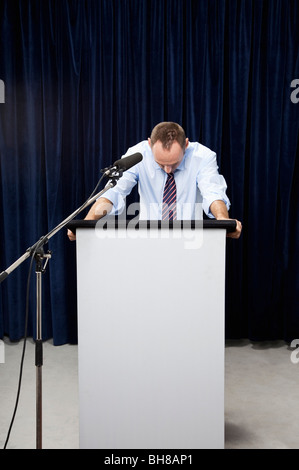 Man standing behind podium with microphone on stage holding trophy ...