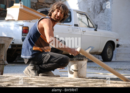A man working outdoors, re-laying cement coving on a stone wall, UK ...