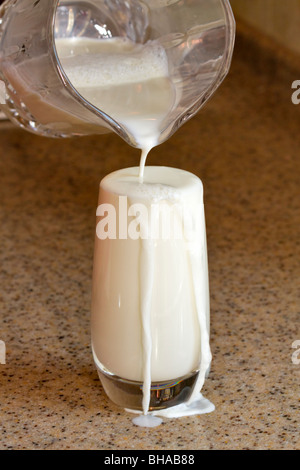 Milk Pouring Into an Overflowing Glass Stock Photo - Alamy