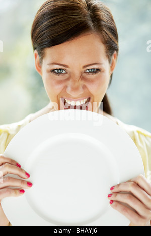 Girl biting plate Stock Photo - Alamy