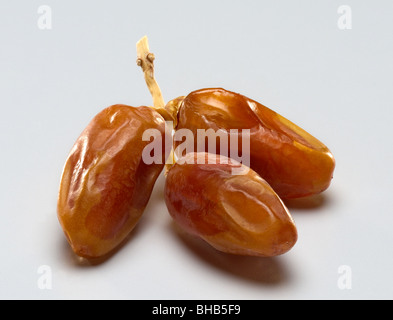 Semi-dried dates and date fruit cut in half lie on palm leaves isolated ...