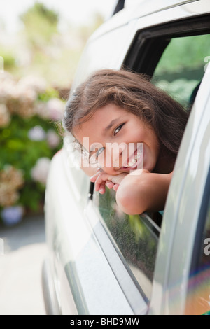A girl is with her head out of a car window while is driving in nature ...