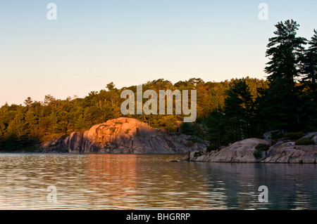 Beautiful reflections of granite rock cliff on George Lake Killarney ...
