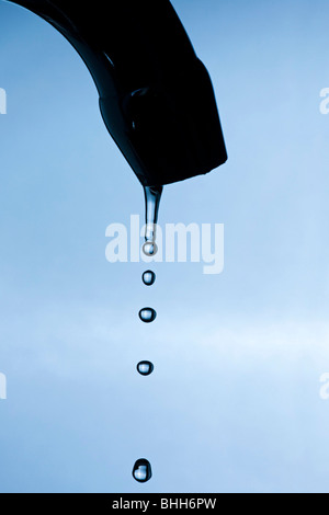 Close-up of a dripping faucet wasting water, highlighting the ...