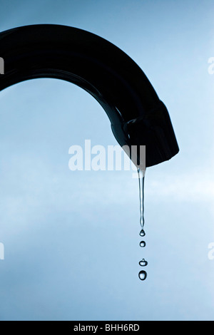 Close-up of a dripping faucet wasting water, highlighting the ...