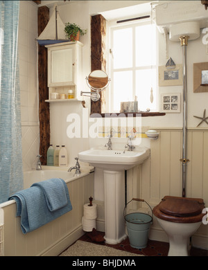 White pedestal basin below window in black+white attic bathroom with ...