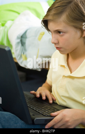 Teen boys in bedroom with laptop computer and textbooks, listening to ...