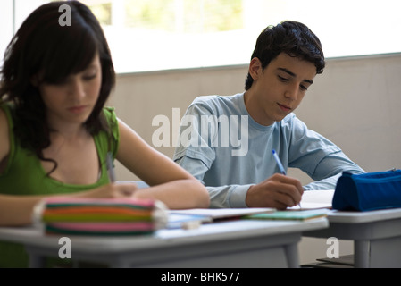 Three high school students doing homework together while sitting on ...
