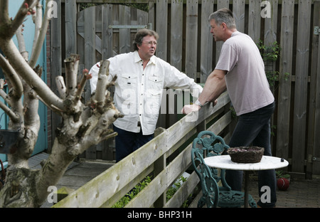 Neighbors talking over the fence Stock Photo - Alamy