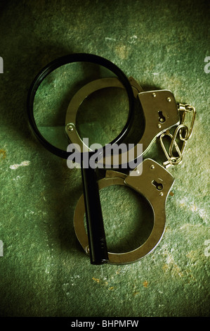 Magnifying glass and handcuffs Stock Photo - Alamy