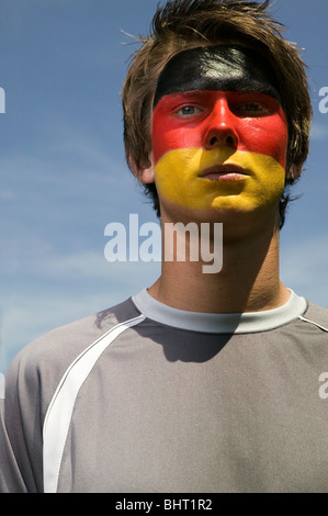 Boy with face paint and German football shirt, kissing soccer ball ...