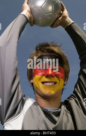 Boy with face paint and German football shirt, kissing soccer ball ...