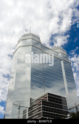 A tall modern building with a round spire on top stands on a ...