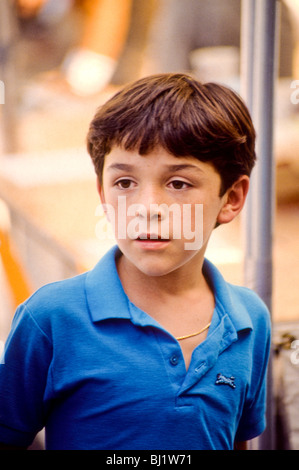 A school-age boy in a field with tall green sunflowers. Country ...