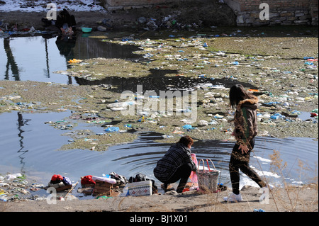 Women washing clothes in a polluted pond in a village in Hebei province ...