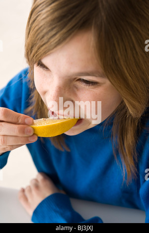 The child eats a sour lemon. The girl wrinkled her face Stock Photo - Alamy