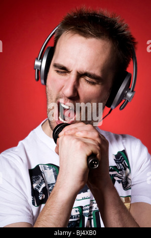 Young man in headphones, with microphone and mobile phone singing on ...