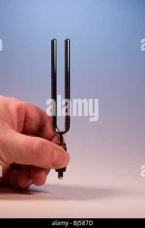 Hand holding tuning fork Stock Photo - Alamy