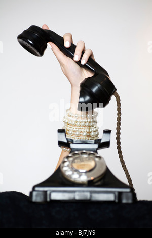 Hand holding vintage telephone receiver over chalkboard background ...
