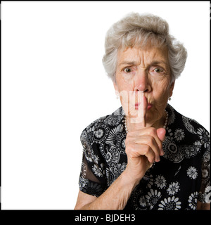 Senior woman shushing camera Stock Photo - Alamy